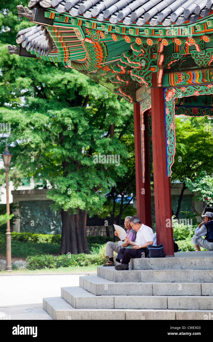 Korean men sit in the shade of a Korean style pavilion in Seoul, Korea ...