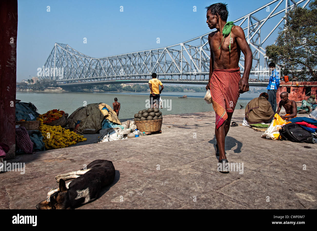 Man walking at Mullick ghat with the massive outline of Howrah Bridge ...