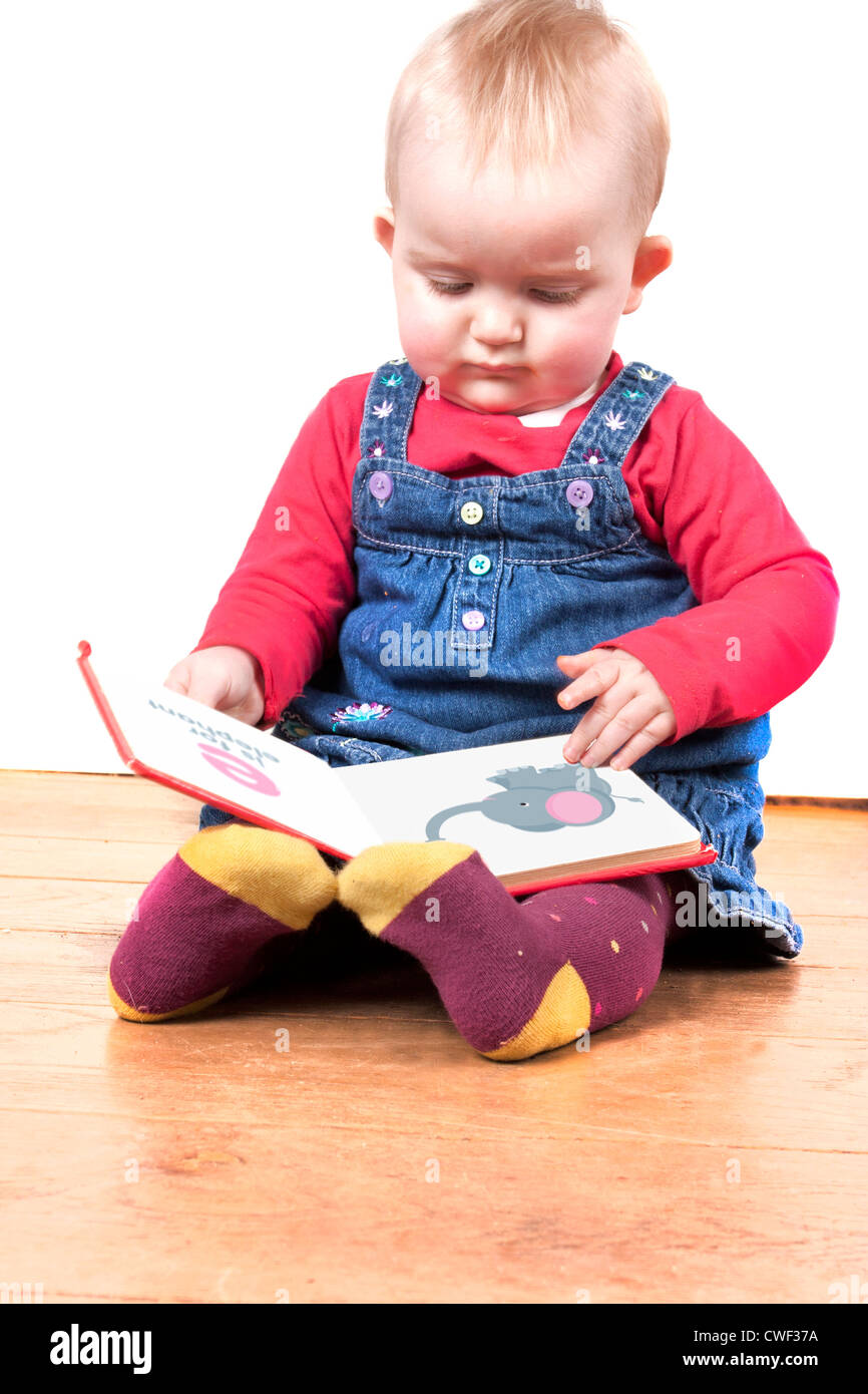 baby girl reading a small picture book isolated on white background ...