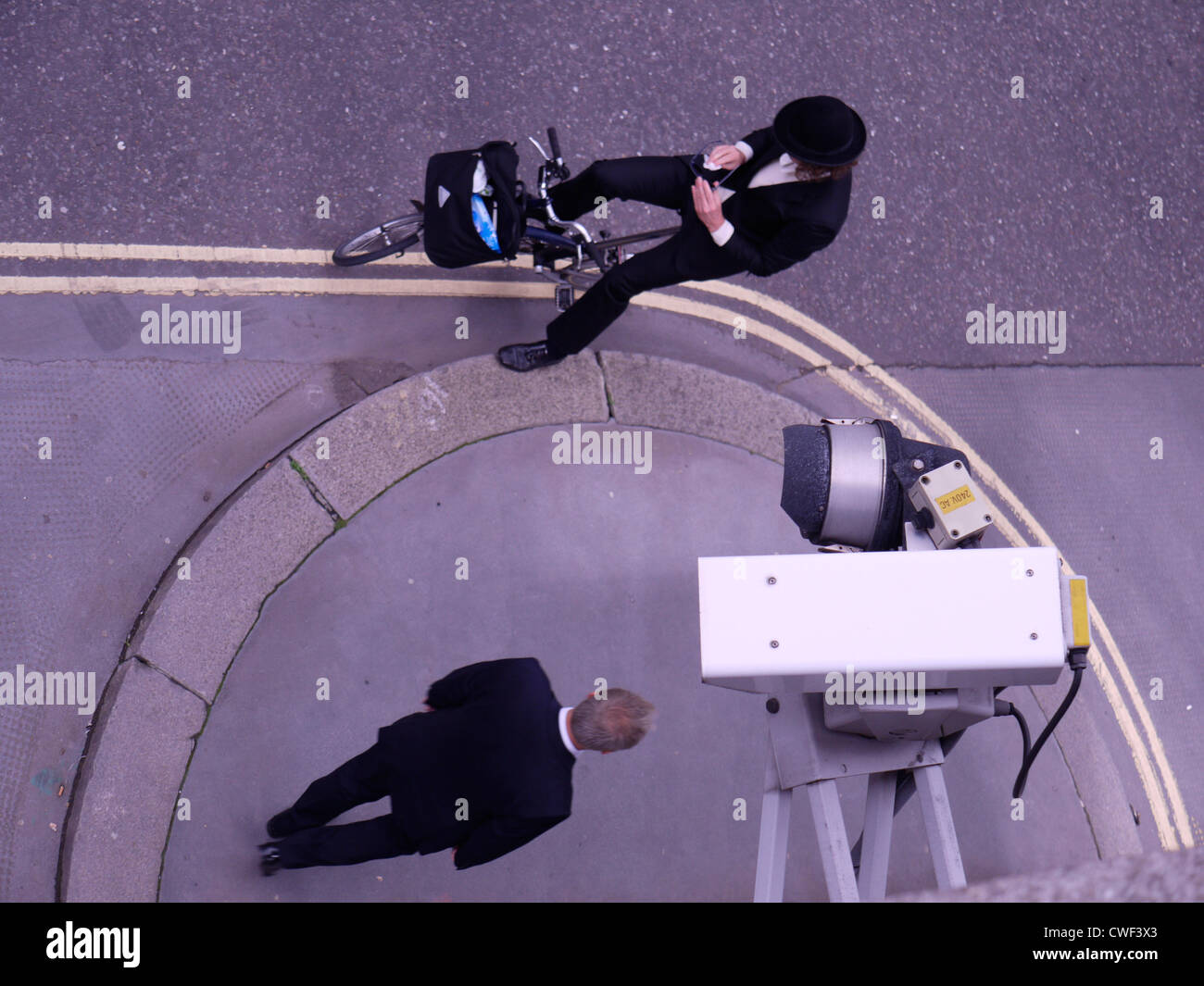 A surveillance CCTV camera overlooks a cyclist wearing a bowler hat in ...
