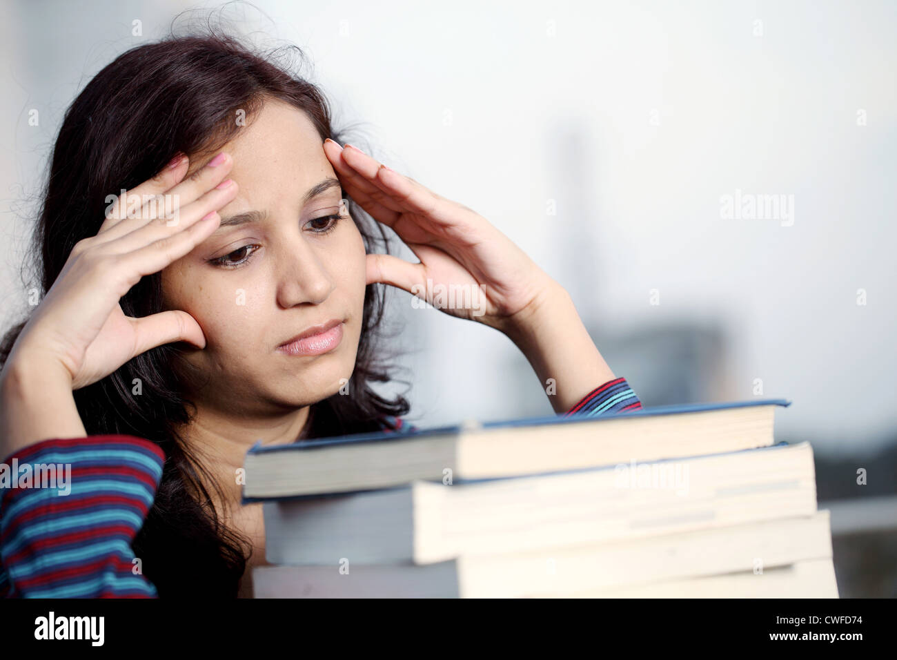 Stressed student with stack of books Stock Photo - Alamy