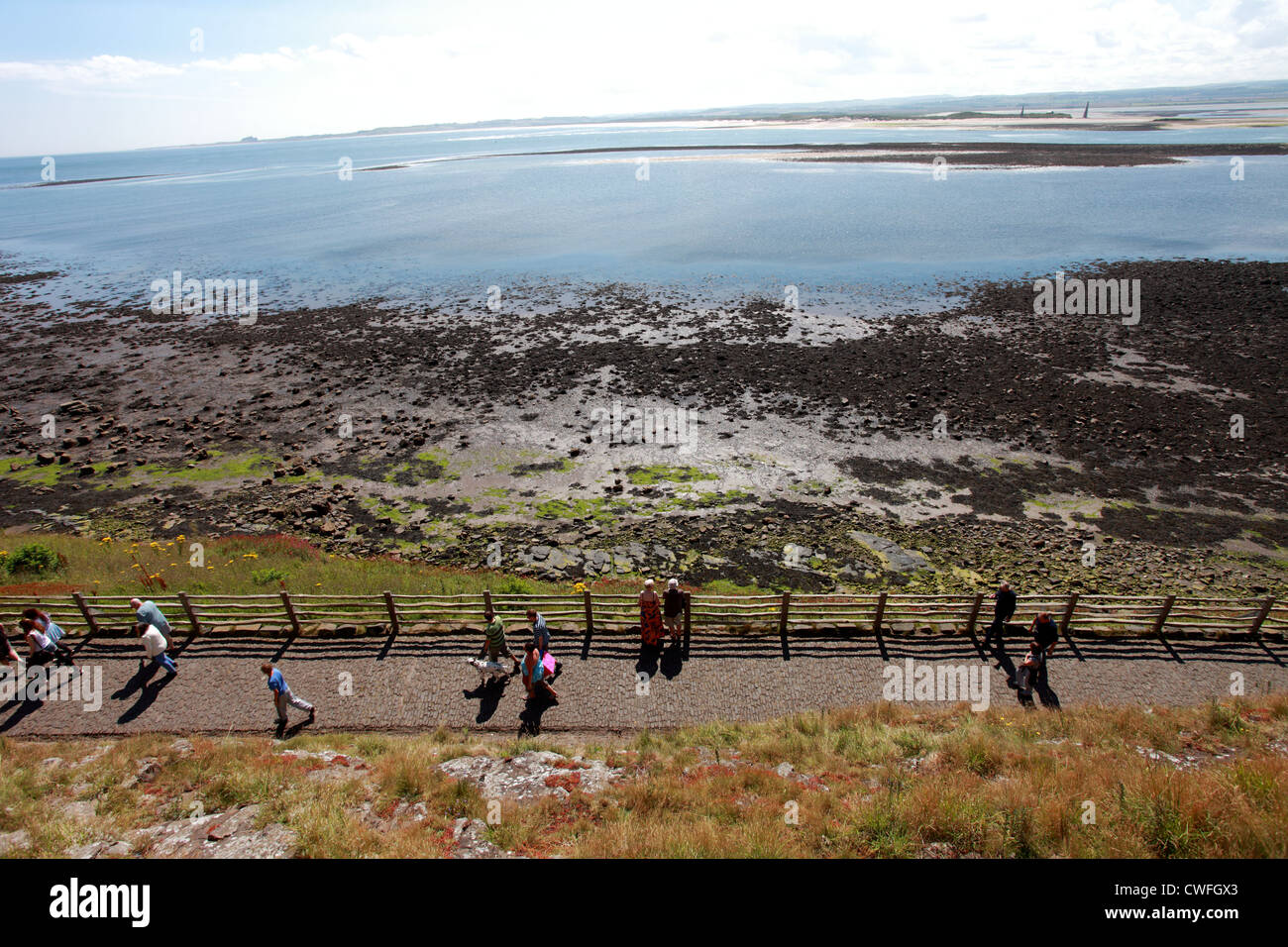 Tourists and vistors on a path below Lindisfarne Castle with the ...