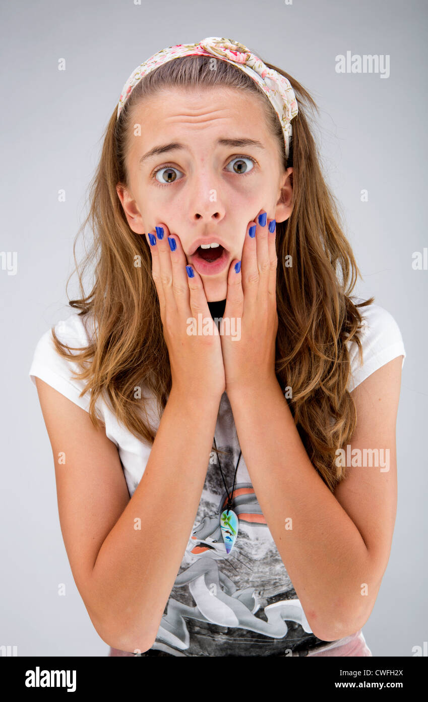 A young teenage girl looking worried or scared, holding her face with ...
