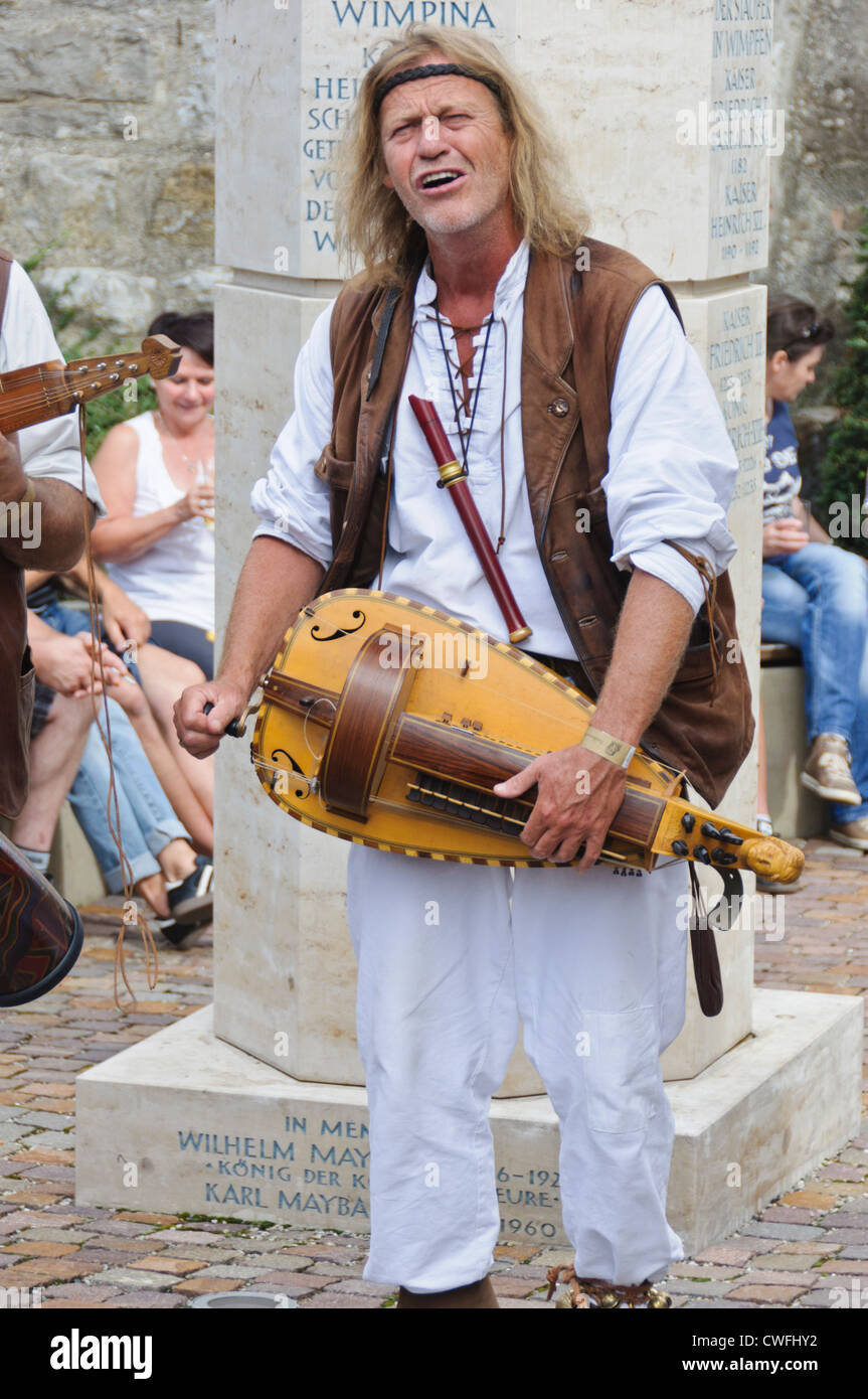 Musician minstrel plays hurdy-gurdy wheel fiddle at a medieval market ...