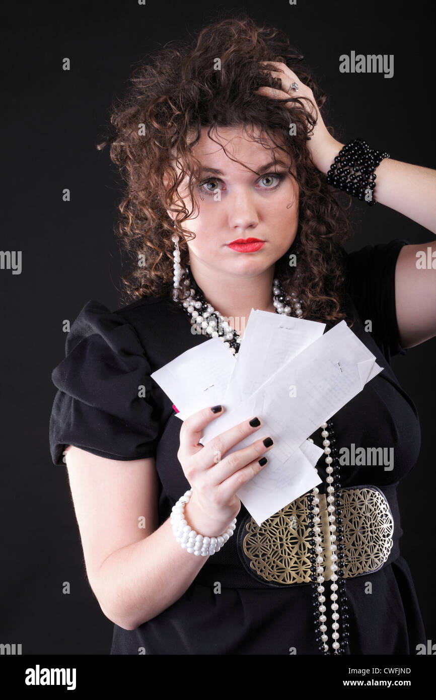 Worried woman calculating her bills shopping over black background ...