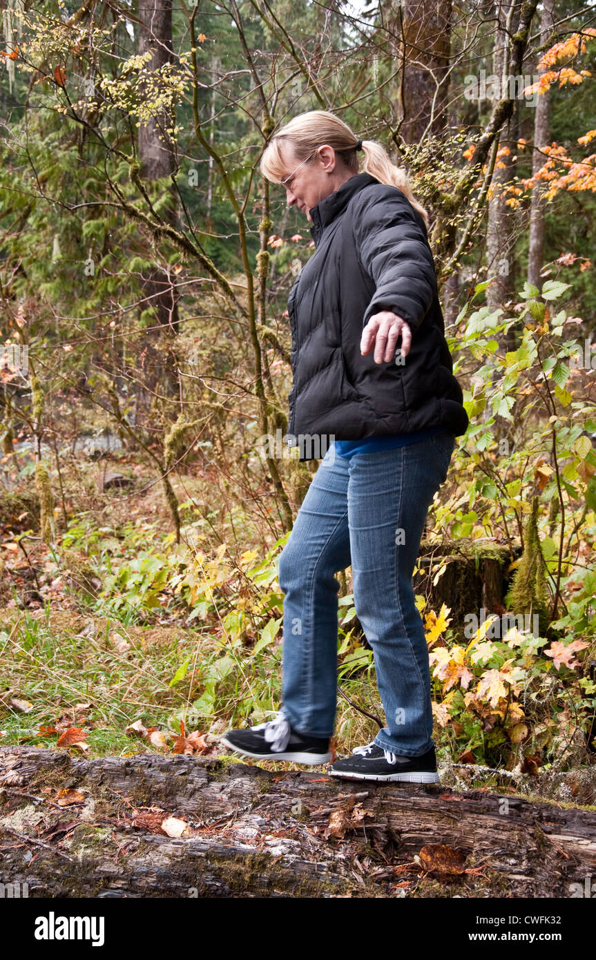 midlife aged Caucasian woman is balancing while walking on a log in the ...