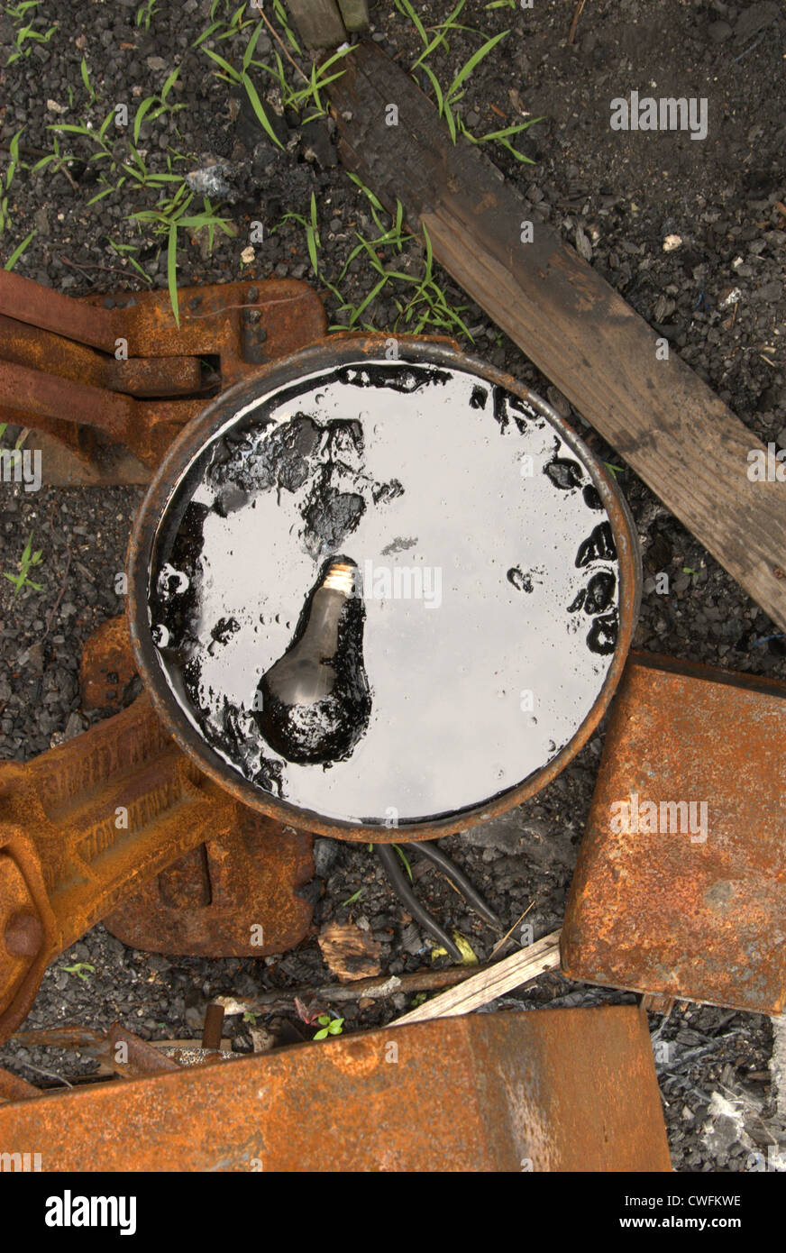 discarded light bulb floating in bucket of toxic waste, surrounded by ...
