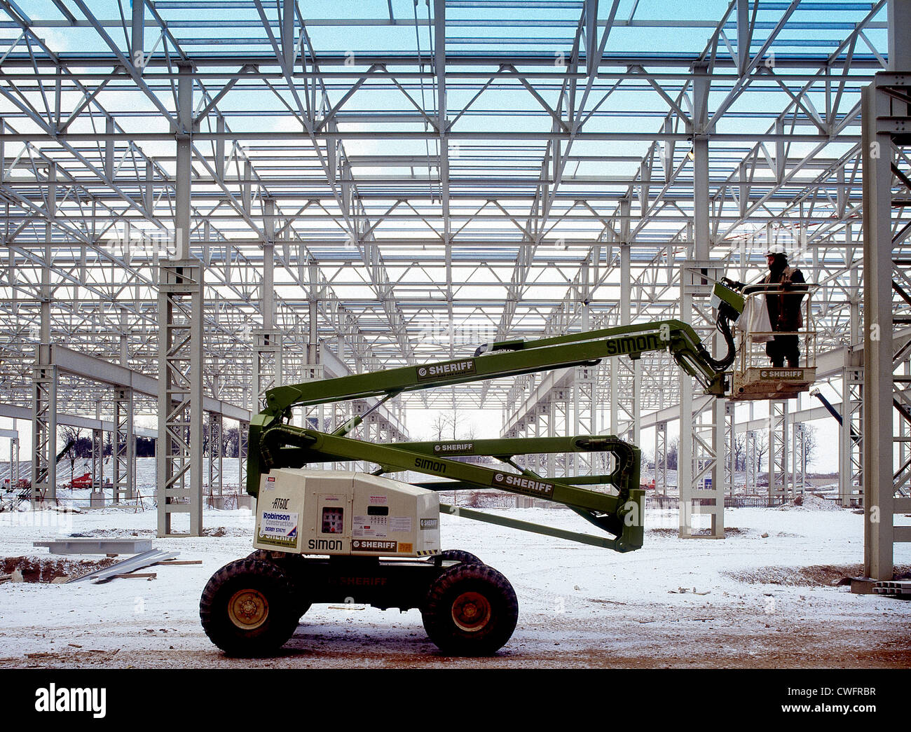Worker in high level platform on a factory building site in the snow ...