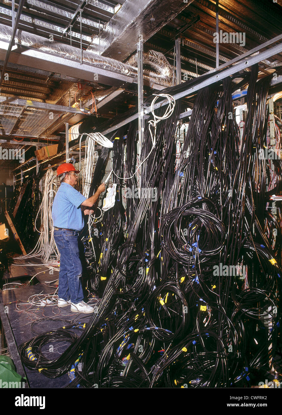 Electrical services engineer working on cabling in commercial offices ...