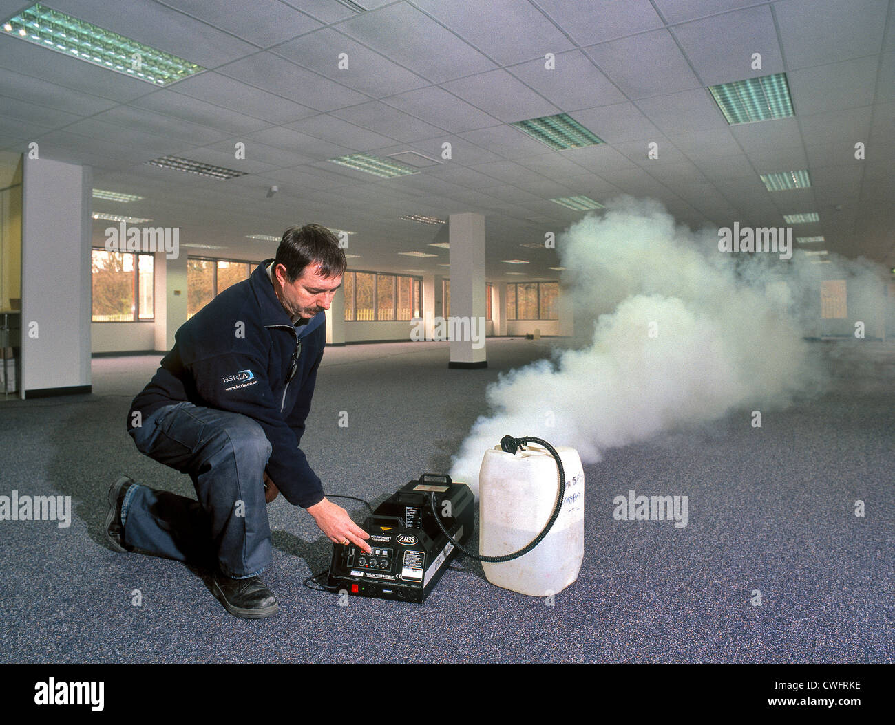 Man conducting a smoke test in an empty office building Stock Photo - Alamy