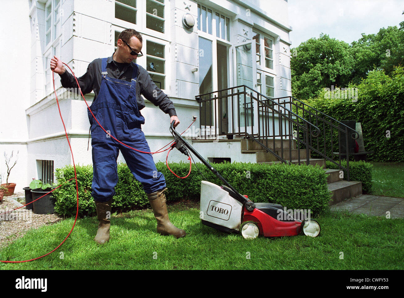 Man mowing the lawn in a garden Stock Photo - Alamy