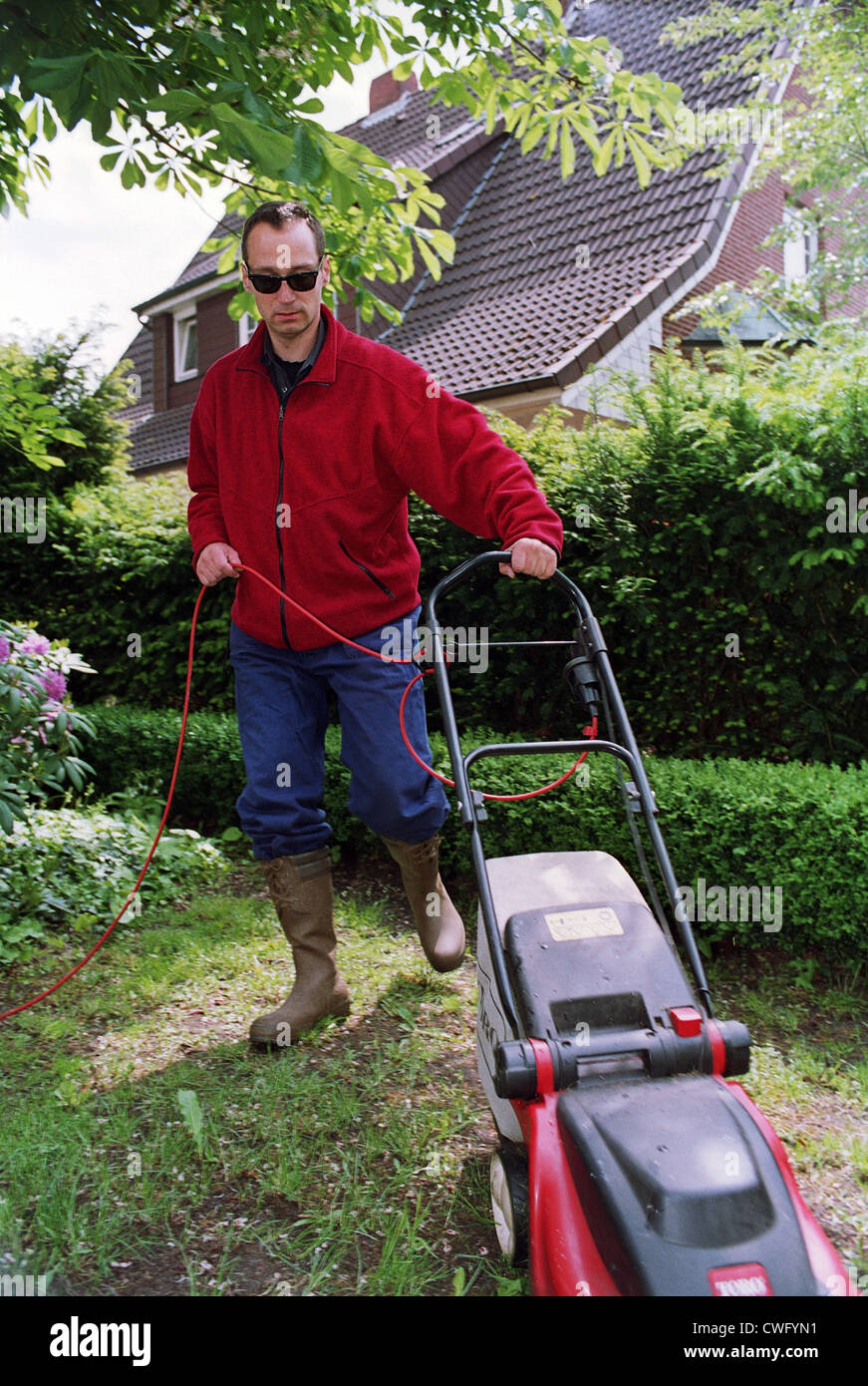 Man mowing the lawn in a garden Stock Photo - Alamy