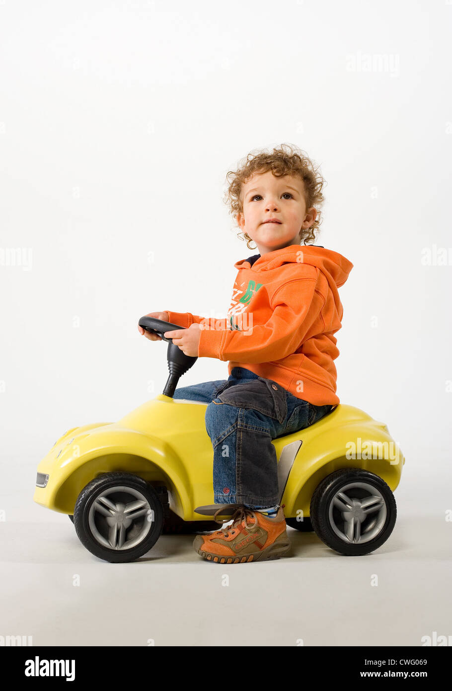 Little boy on a yellow toy car Stock Photo - Alamy