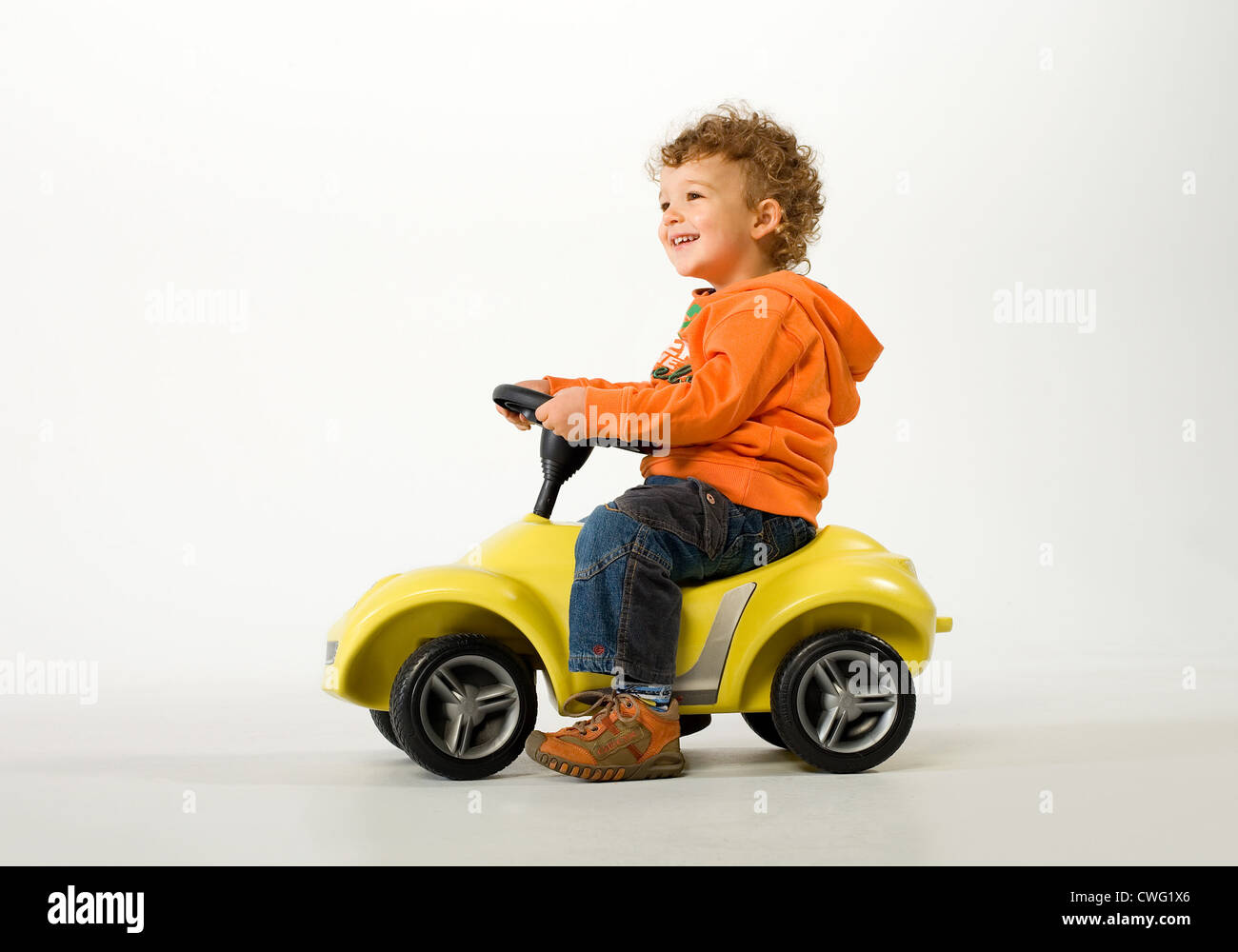 Little boy on a yellow toy car Stock Photo - Alamy