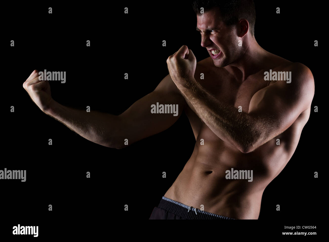 Angry muscular man in attack pose on black Stock Photo - Alamy
