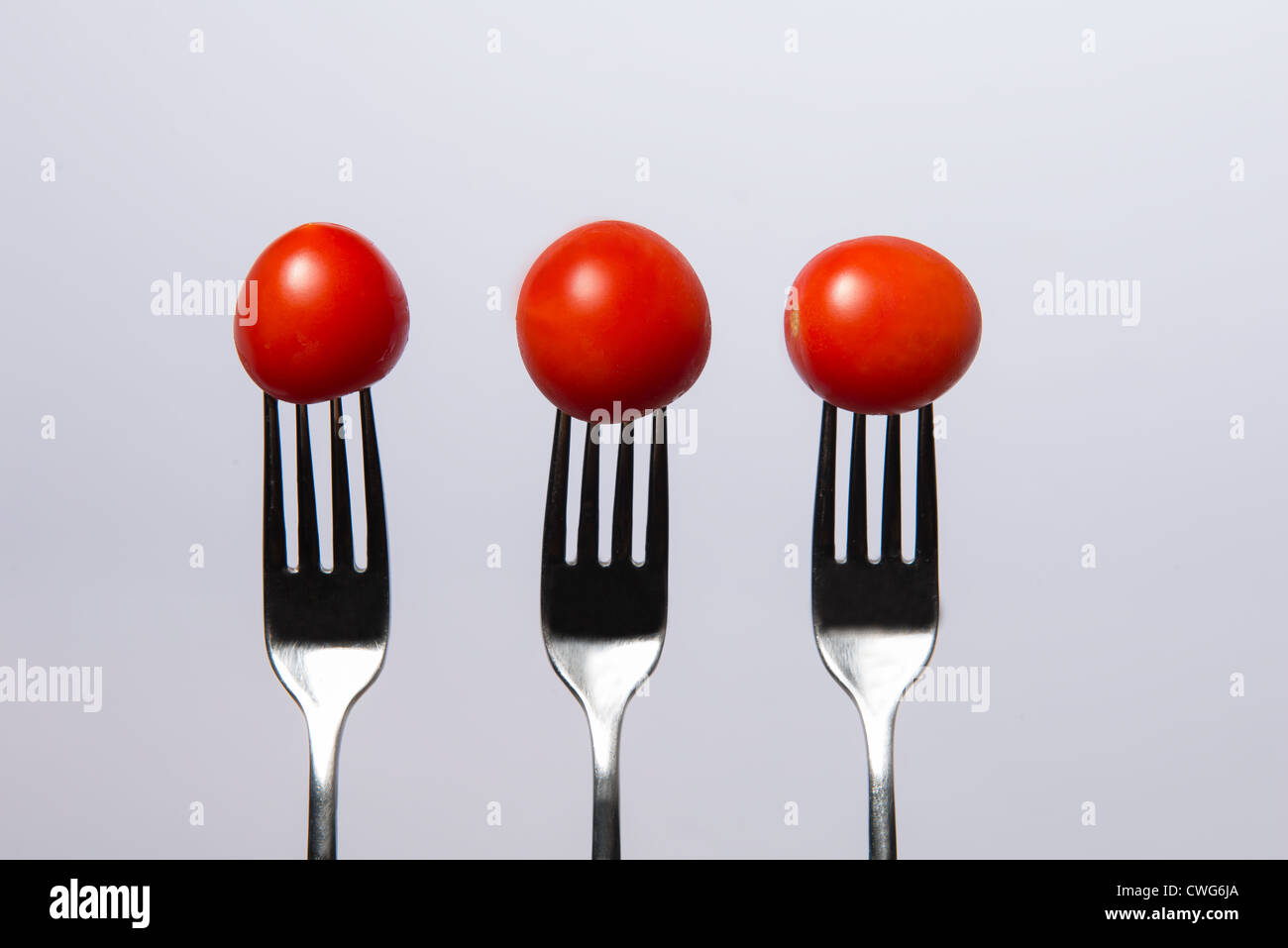 three forks and three tomatoes Stock Photo - Alamy