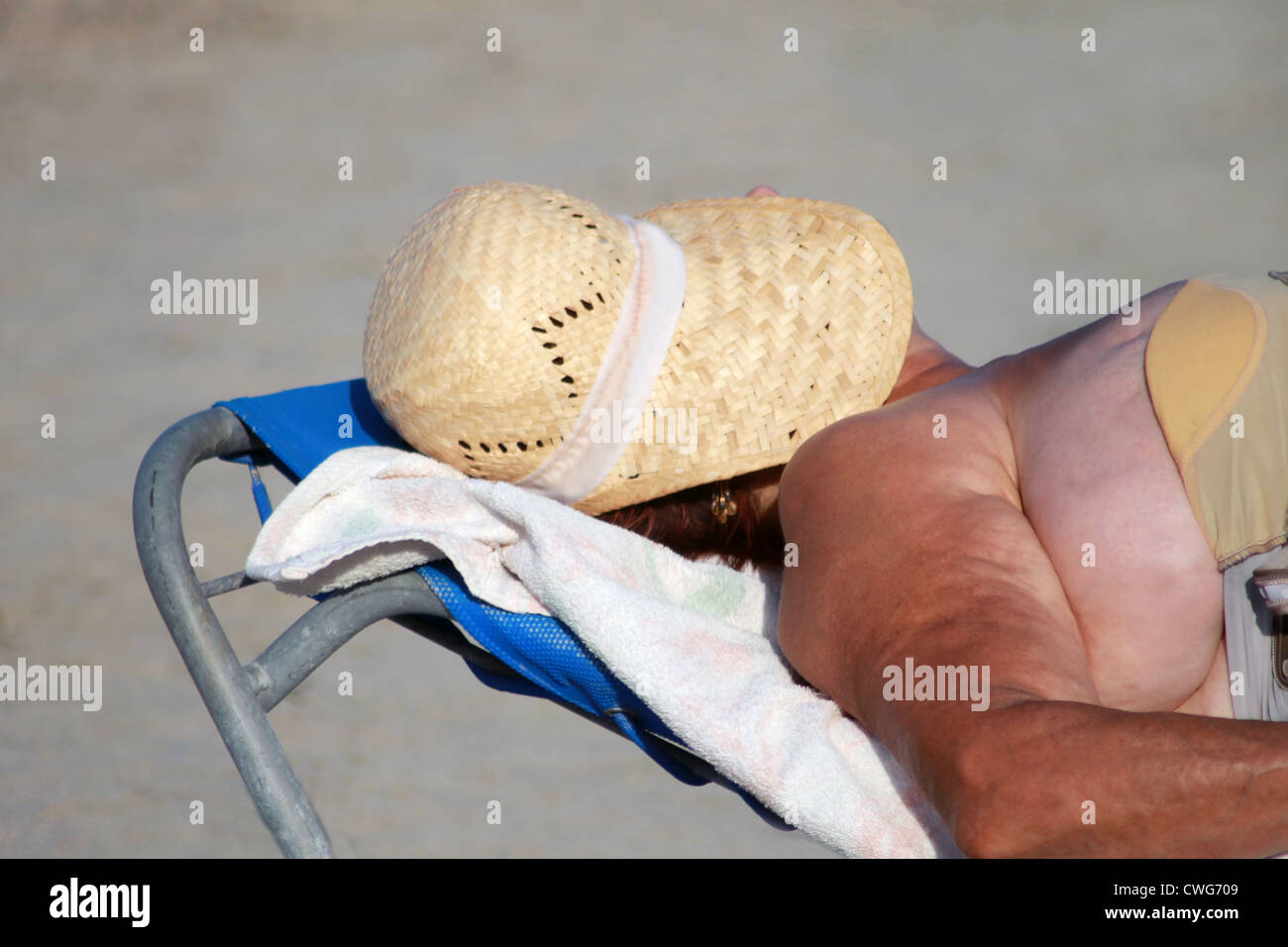 Senior woman sunbathing on beach with hat covering face Stock Photo - Alamy