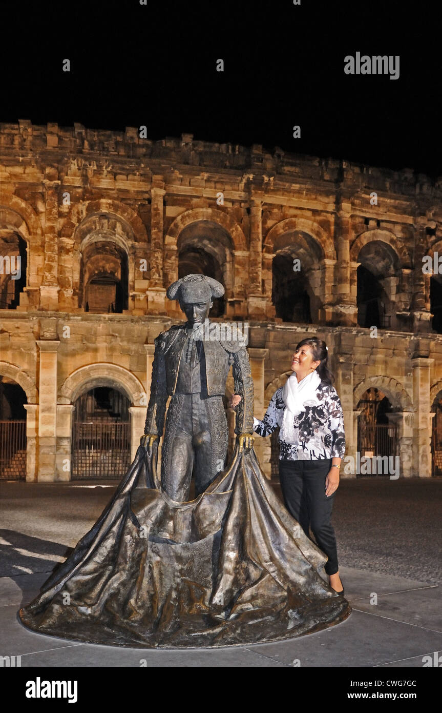 Lady tourist posing at night by bronze statue of matador Bull Fighter ...