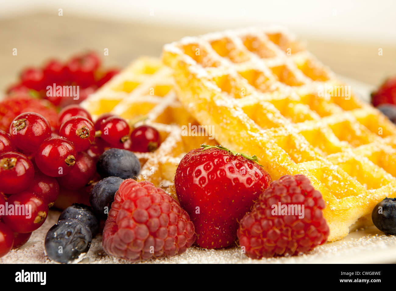 fresh tasty waffer with powder sugar and mixed fruits on wooden ...