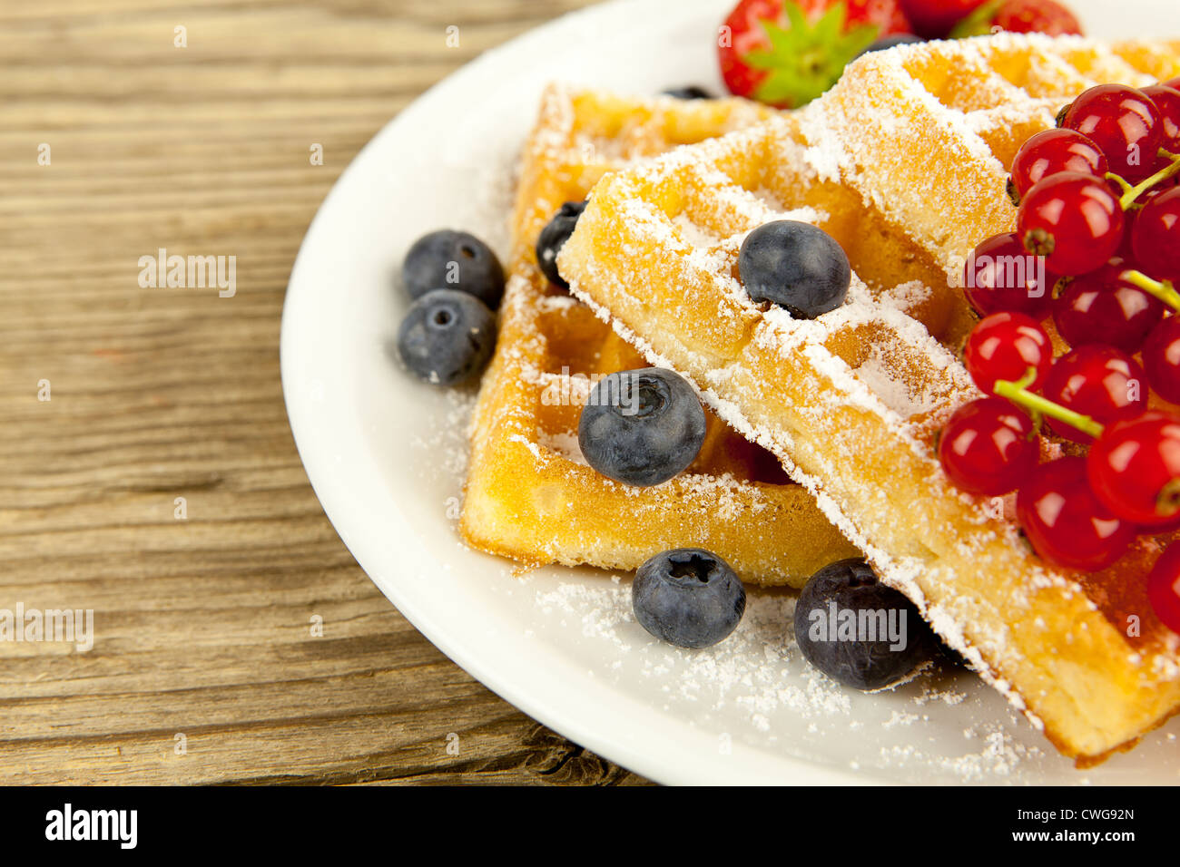 fresh tasty waffer with powder sugar and mixed fruits on wooden ...