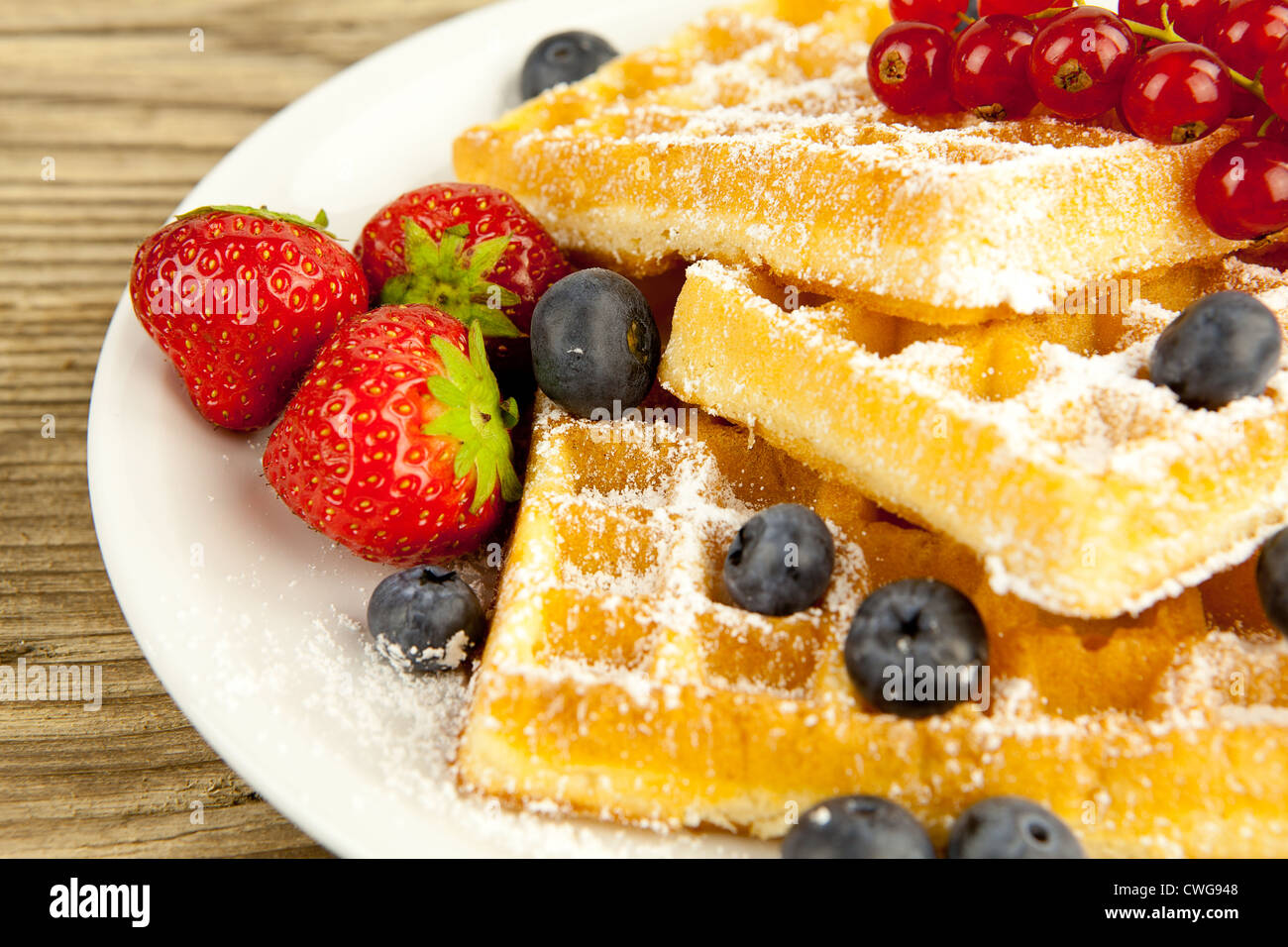 fresh tasty waffer with powder sugar and mixed fruits on wooden ...