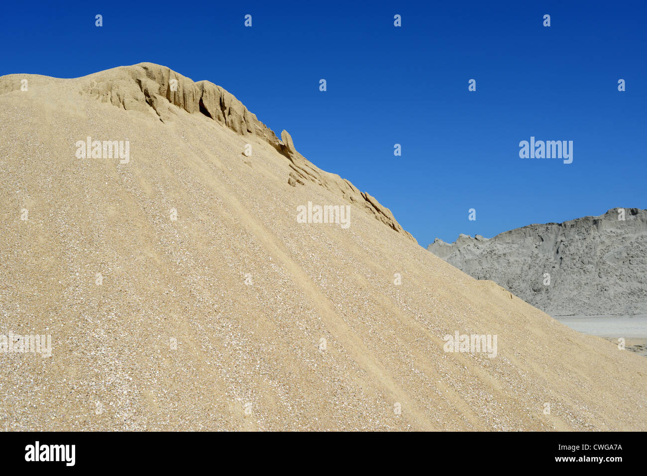 Brown sand mound against blue sky Stock Photo - Alamy