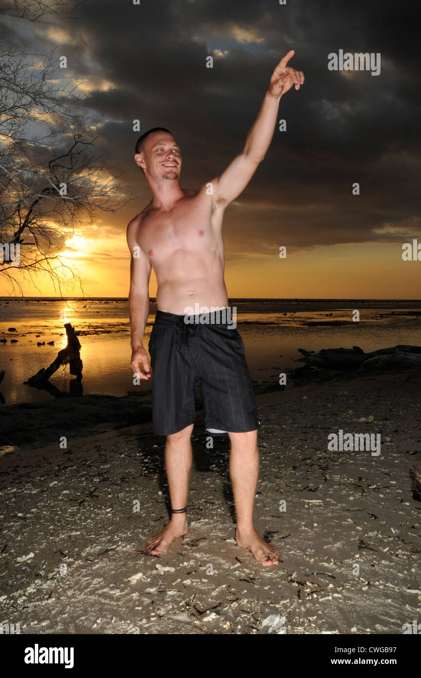 man posing on a beach with sunset pointing Stock Photo - Alamy
