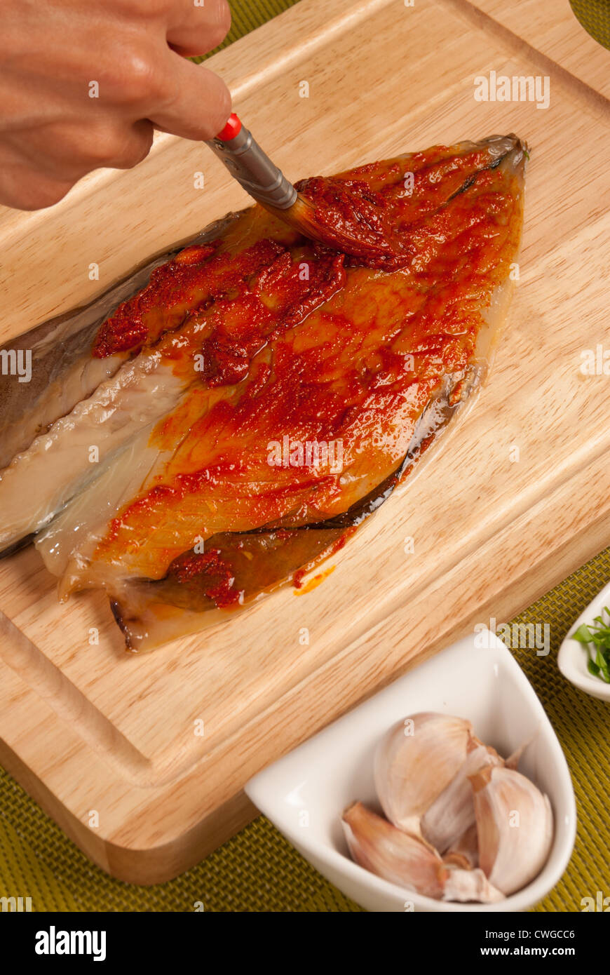 Applying a spicy Mediterranean marinade on a mackerel Stock Photo - Alamy