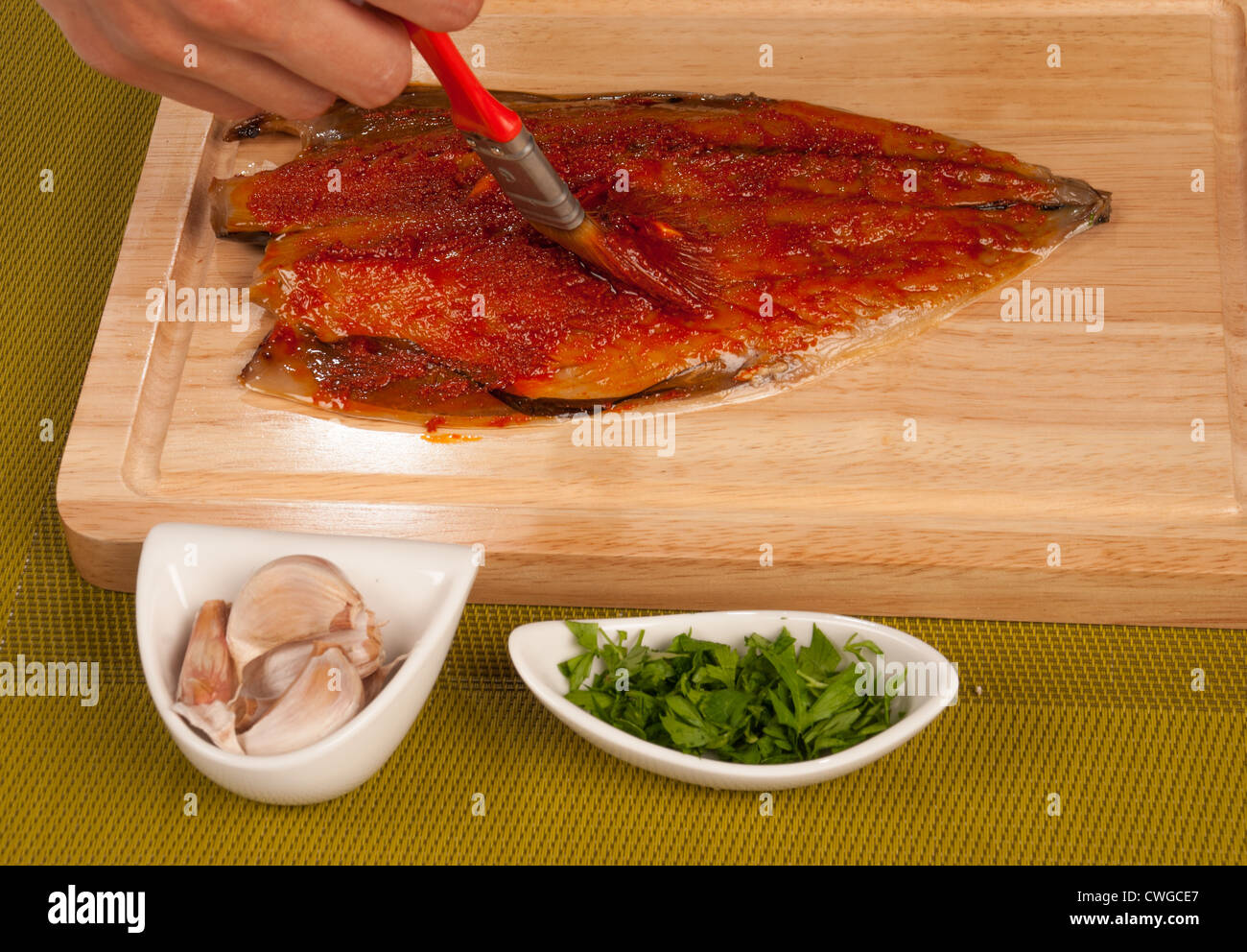 Brushing a fresh mackerel with a savory marinade Stock Photo - Alamy