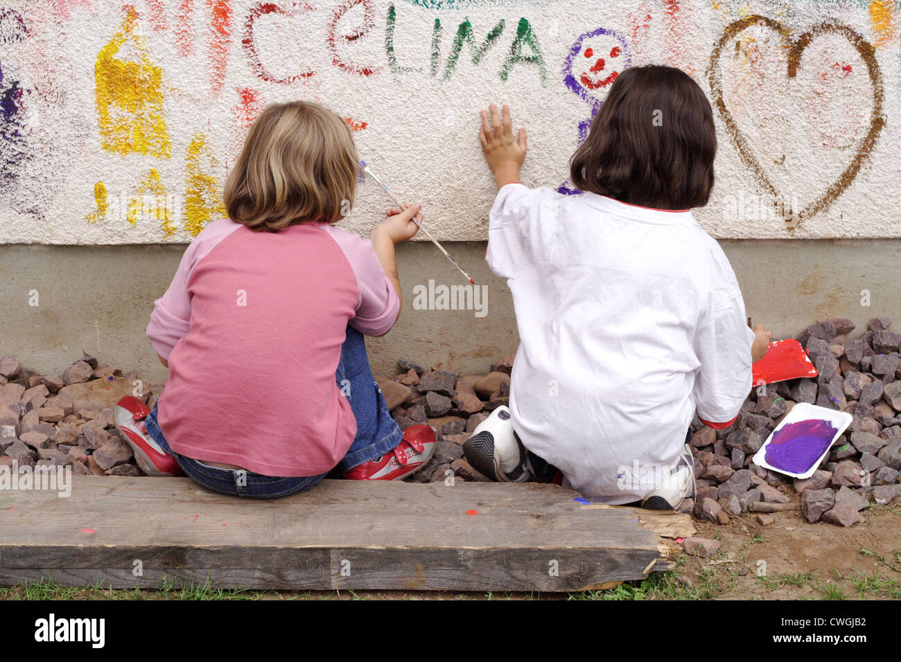 Two girls painting and printing on a house wall Stock Photo - Alamy