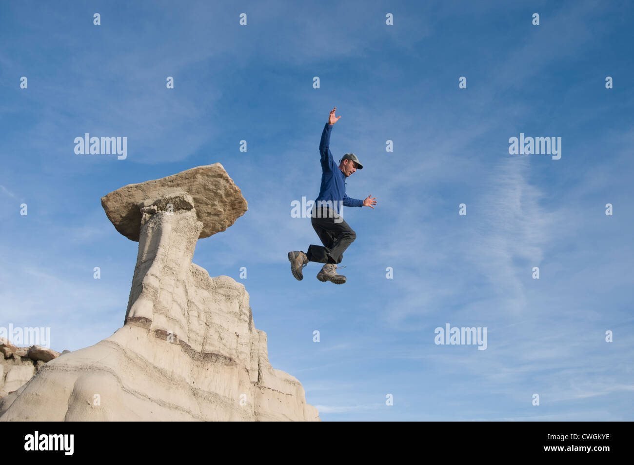 A man jumping off a sandstone rock formation, Bisti Badlands ...