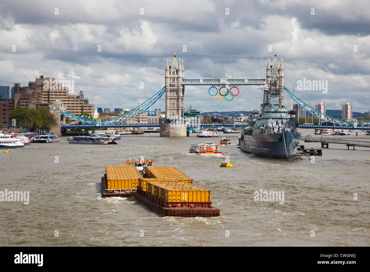 Thames river barge making its way towards Tower Bridge, past HMS ...