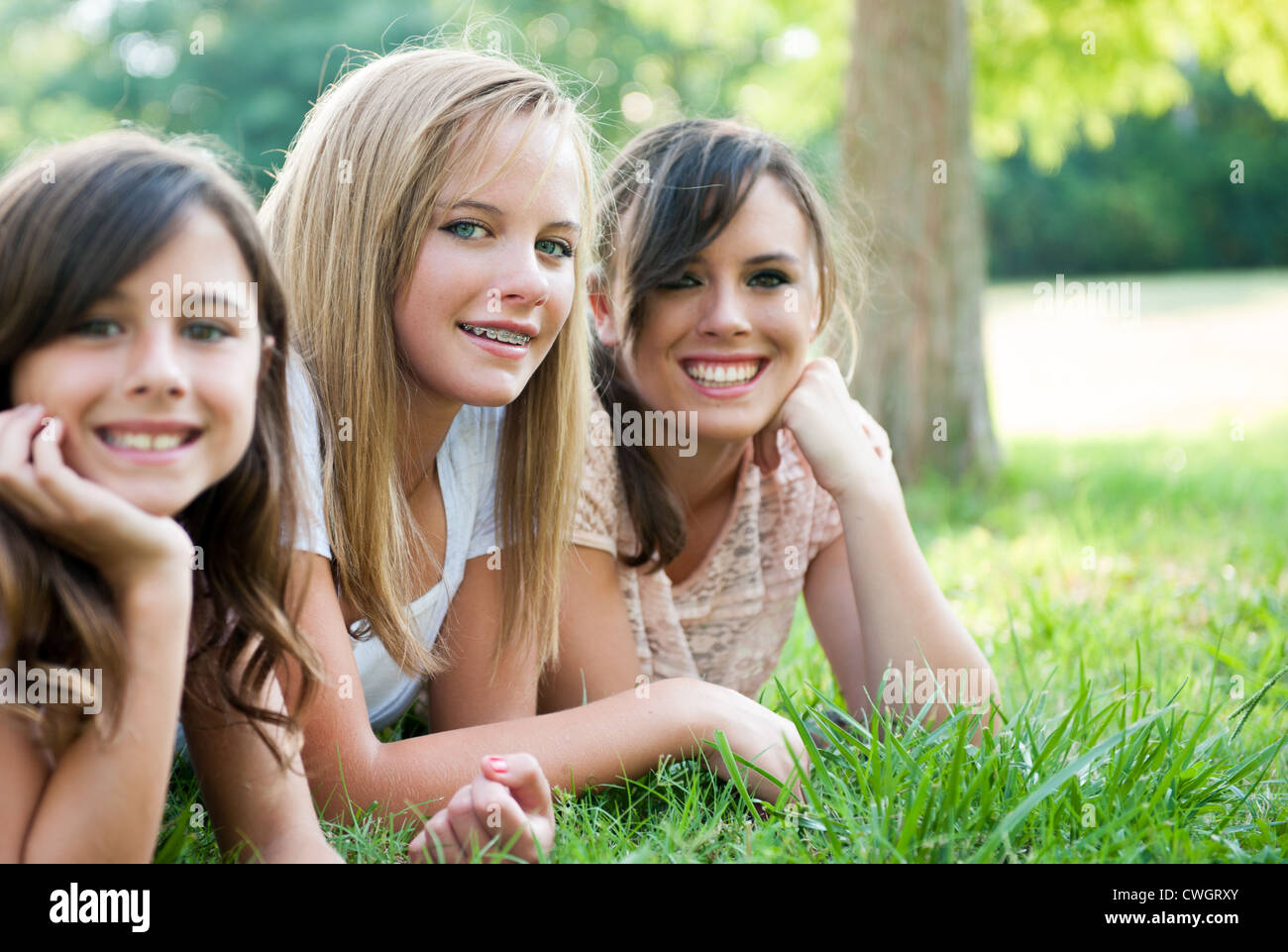 Three sisters laying in the grass smiling Stock Photo - Alamy