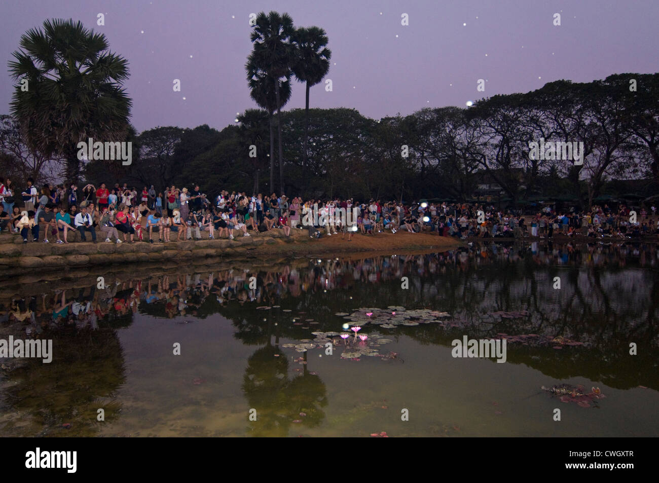 Horizontal view of tourists sitting together around a lake watching the ...