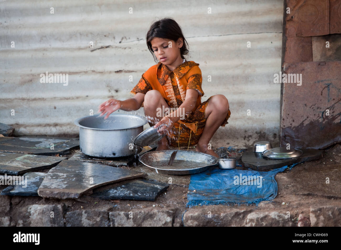 Young Indian girl cleaning pots outside her home in Hampi bazaar Stock ...