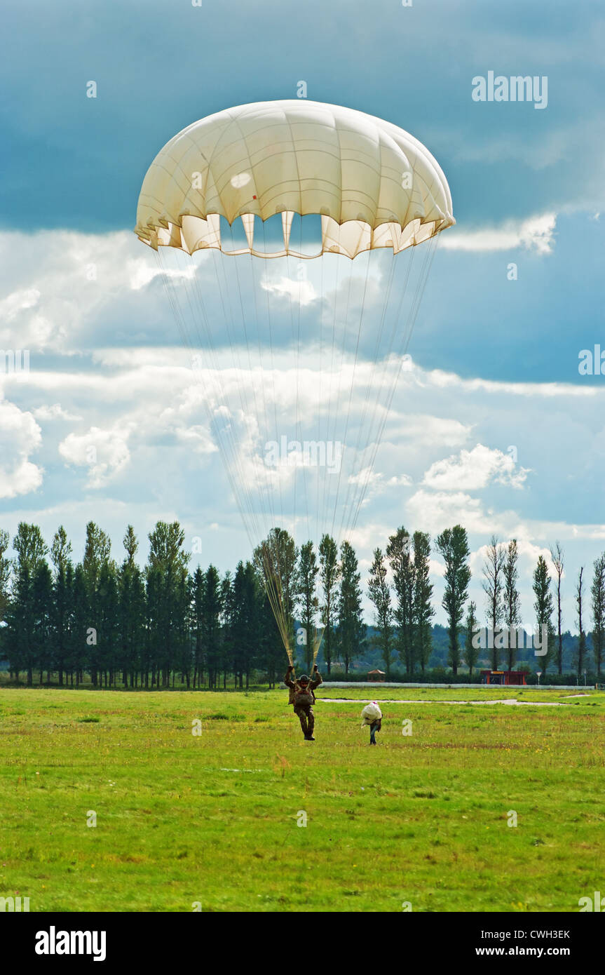 Parashutist landing on green grass airfield Stock Photo - Alamy