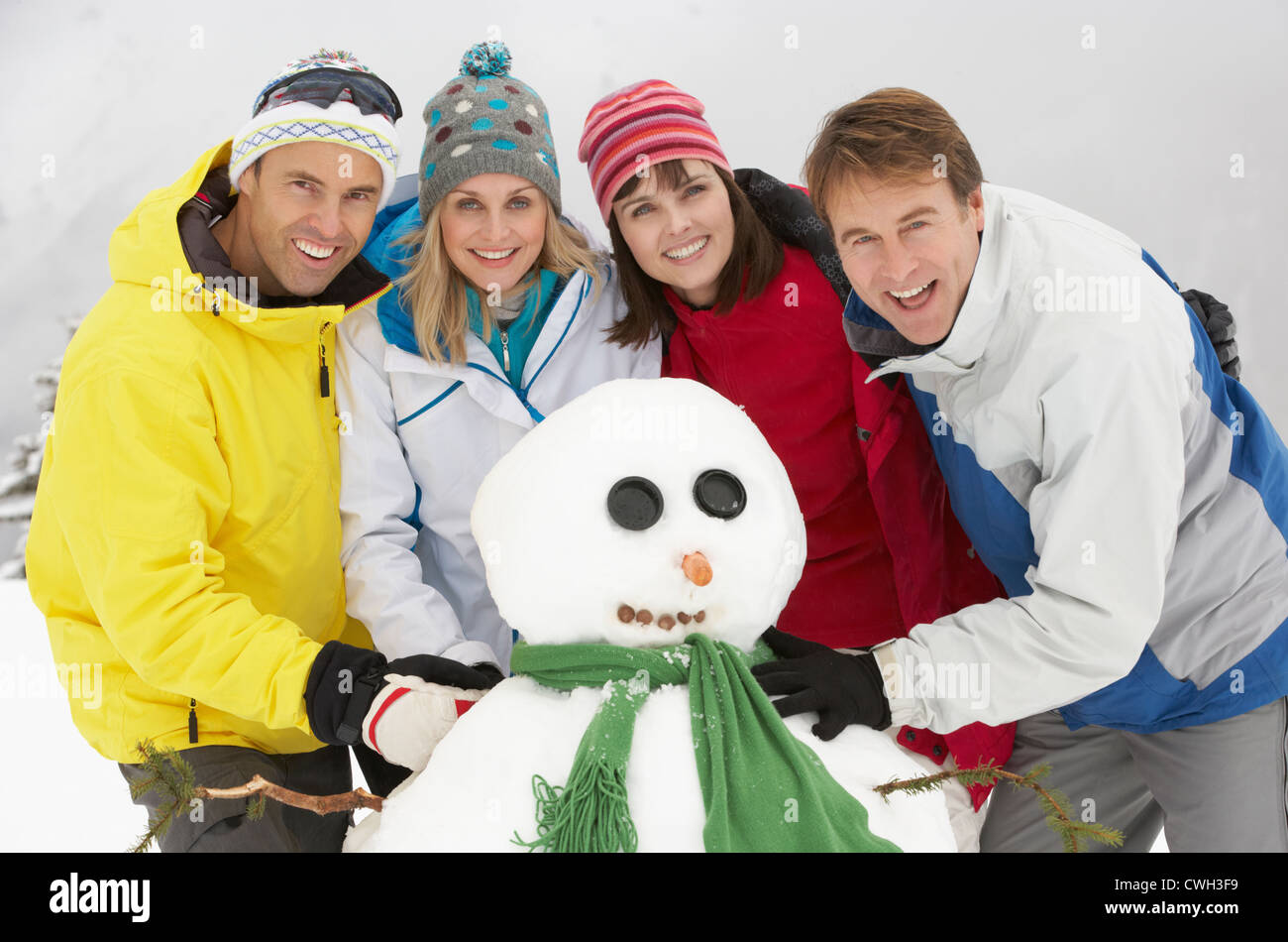 Group Of Friends Building Snowman On Ski Holiday In Mountains Stock ...