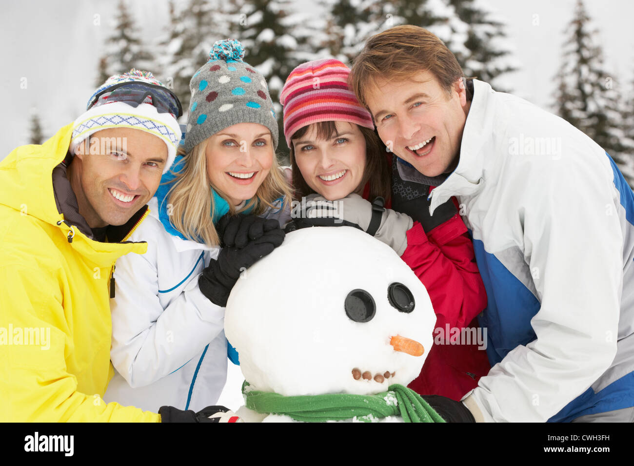 Group Of Friends Building Snowman On Ski Holiday In Mountains Stock ...