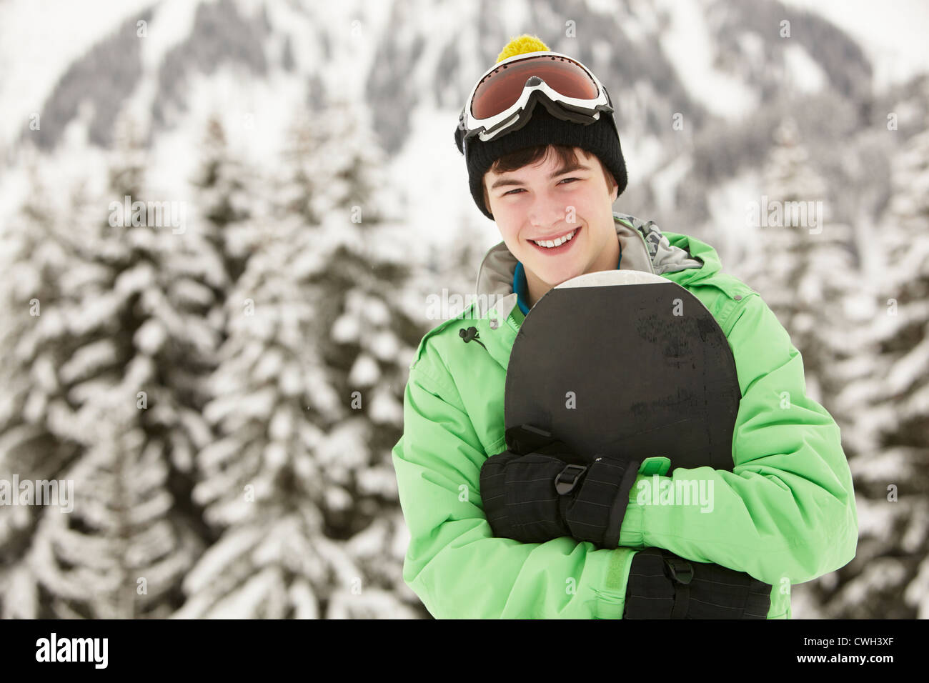 Teenage Boy With Snowboard On Ski Holiday In Mountains Stock Photo - Alamy