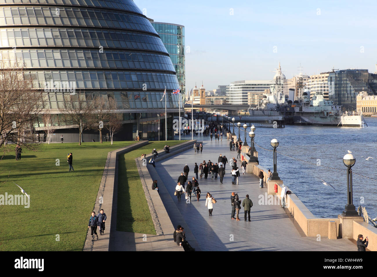 Tourists walking along the Queen's Walk, by the river Thames and past ...