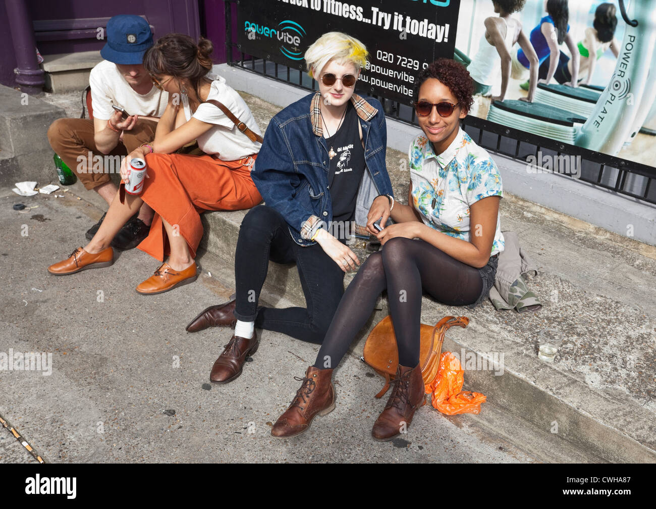 Trendy young people sitting on the pavement at the Notting Hill ...