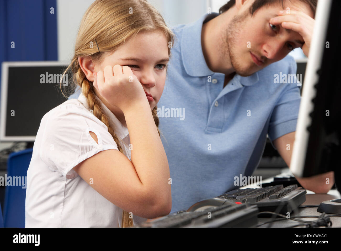 Unhappy teacher and girl using computer in class Stock Photo - Alamy