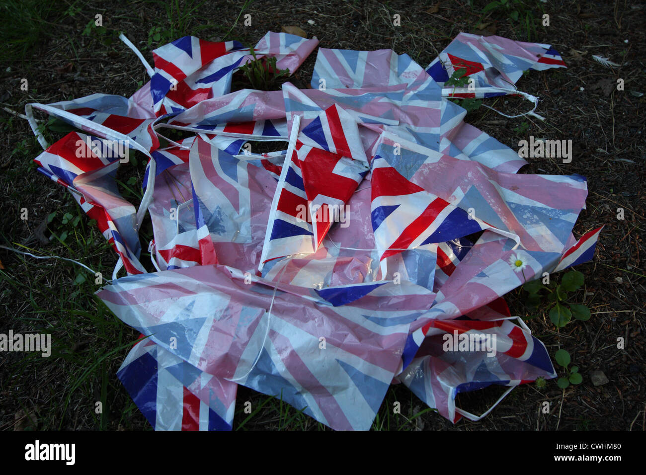 Plastic Union Jack bunting lying on grass ground after a celebration ...