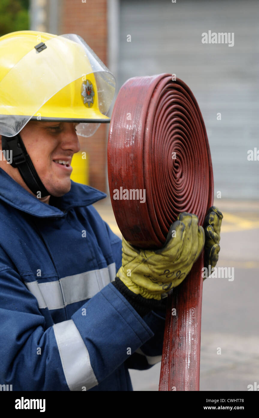A fireman coiling up a hose during an exercise with white watch at ...