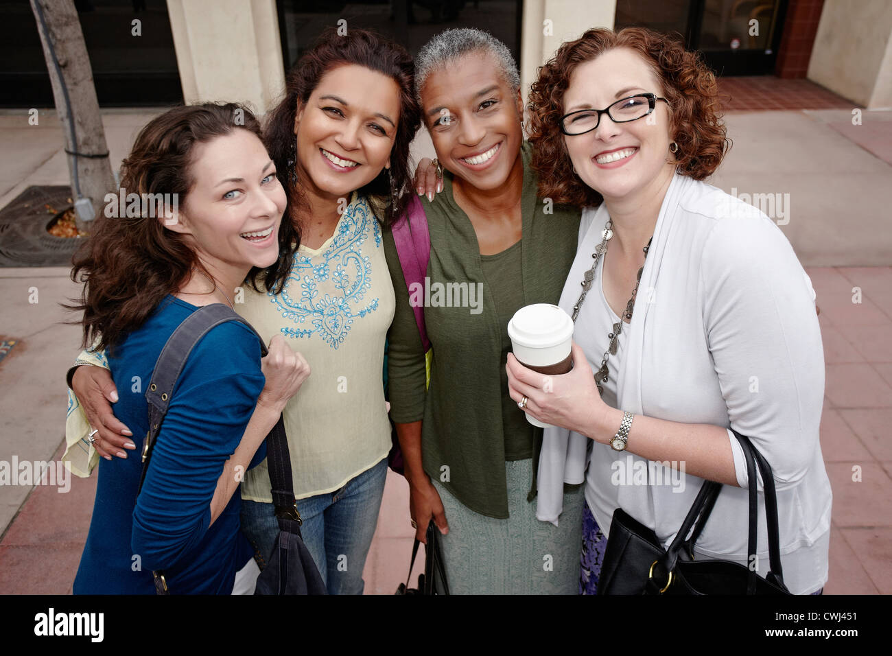 Smiling friends standing on sidewalk Stock Photo - Alamy