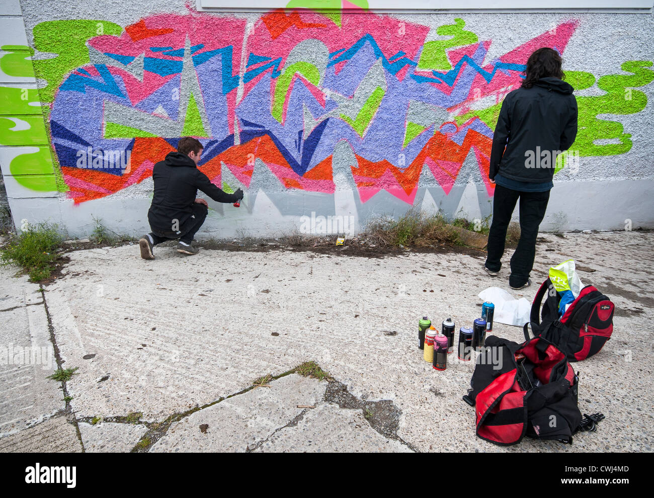Black hooded teenagers spraying walls with graffiti Stock Photo - Alamy