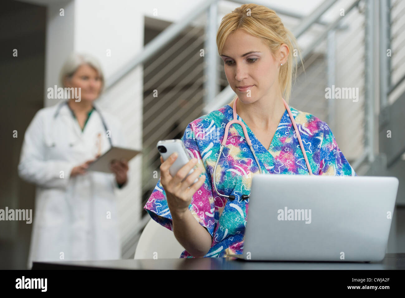 Caucasian nurse using cell phone and laptop Stock Photo - Alamy