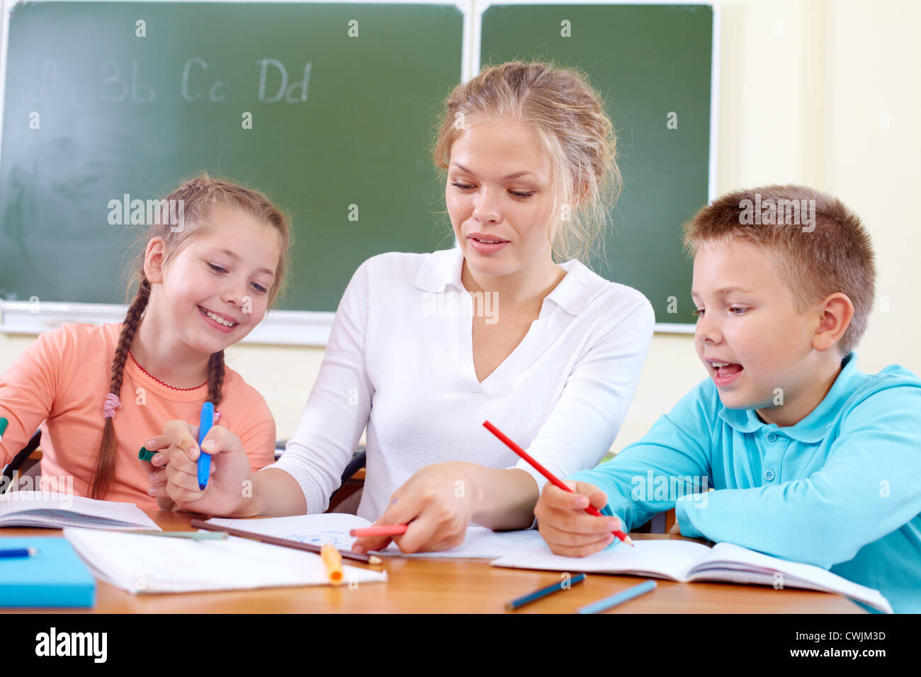 Portrait of two classmates and their teacher drawing with highlighters ...