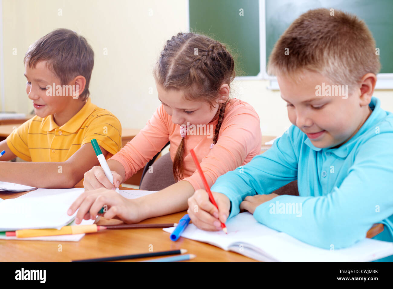 Portrait of lovely girl and her classmates drawing with highlighters at ...