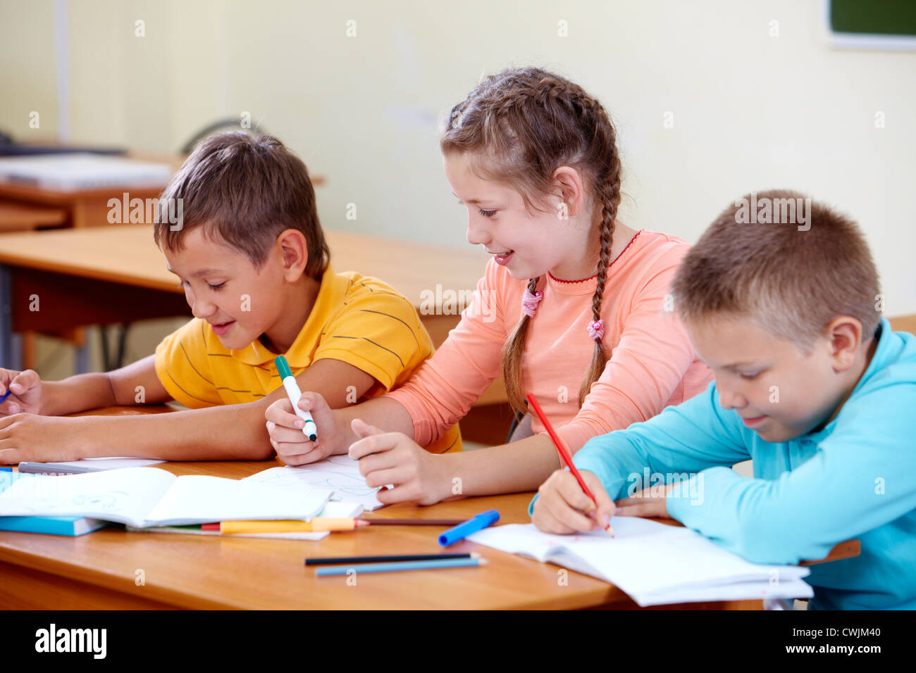 Portrait of lovely girl and her classmates drawing with highlighters at ...